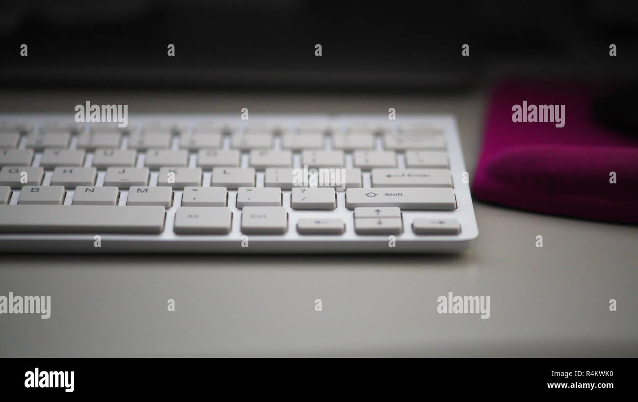 slim white minimalistic keyboard close up in dark night lit by screen ...
