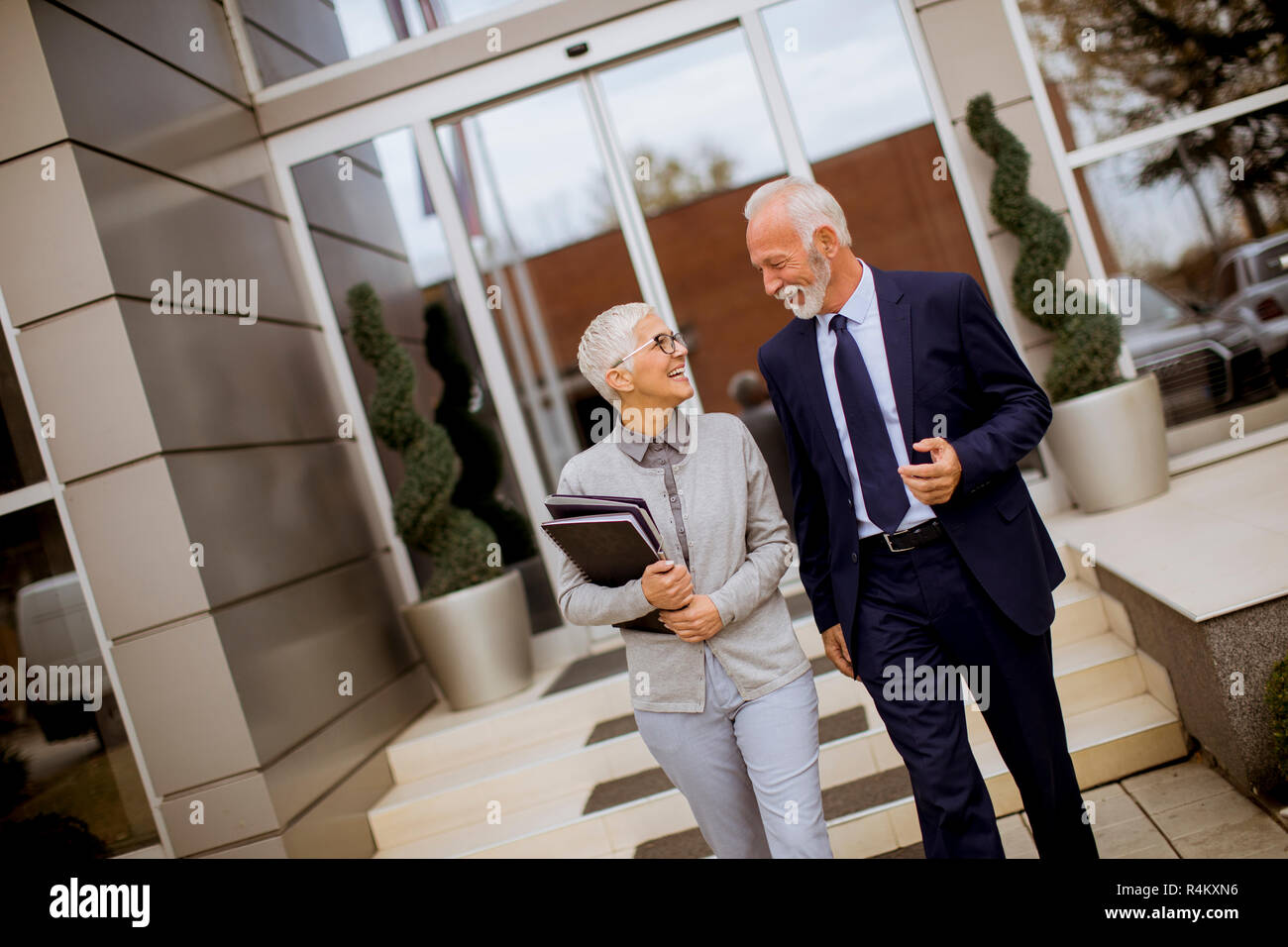 Senior businesspeople standing and talking outdoor office building ...
