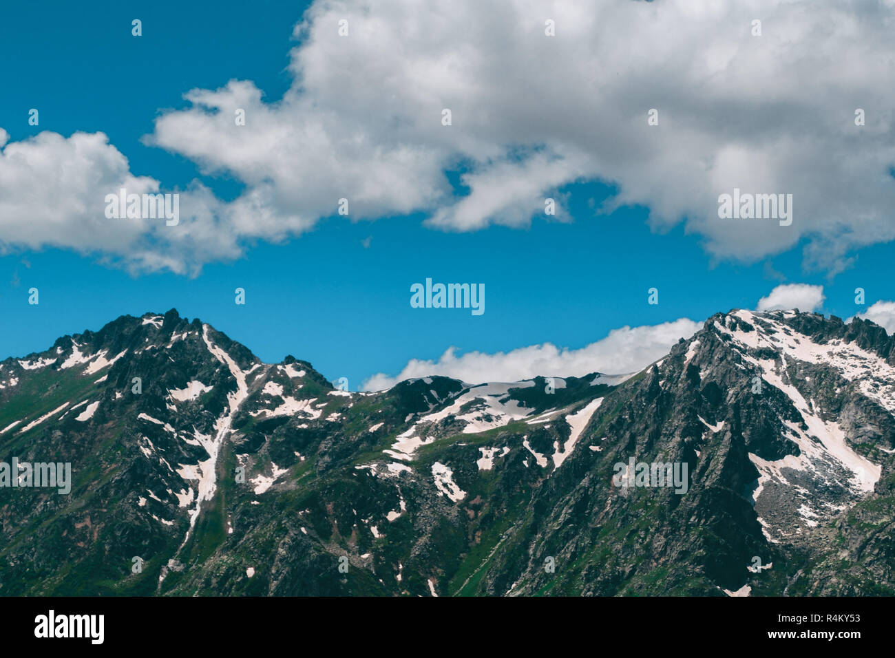 half snowy mountain peaks spring landscape with cloudy sky Stock Photo ...