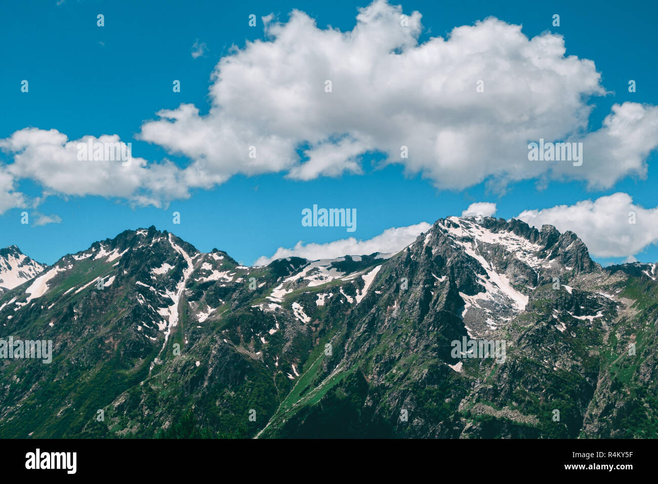 half snowy mountain peaks spring landscape with cloudy sky Stock Photo ...