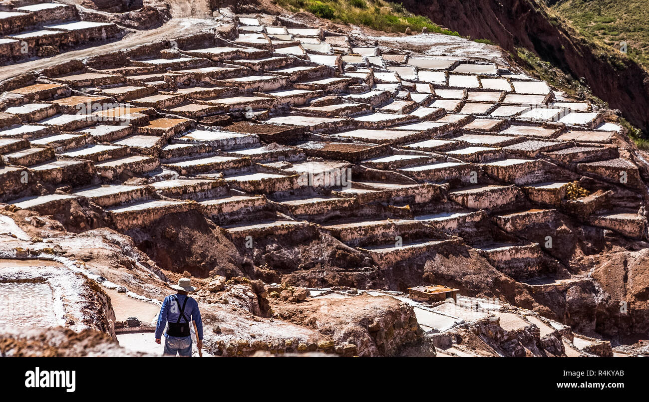 Salt mines and basins with peruvian worker in front, Salineras de Maras ...
