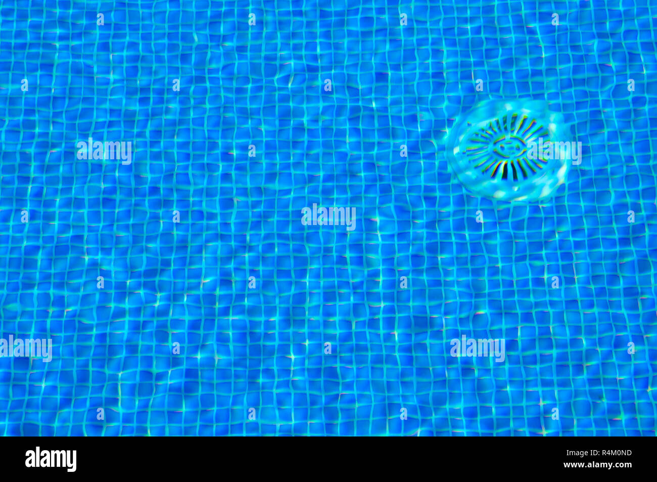 Detail of mosaic tile floor and drain cover in a swimming pool seen ...