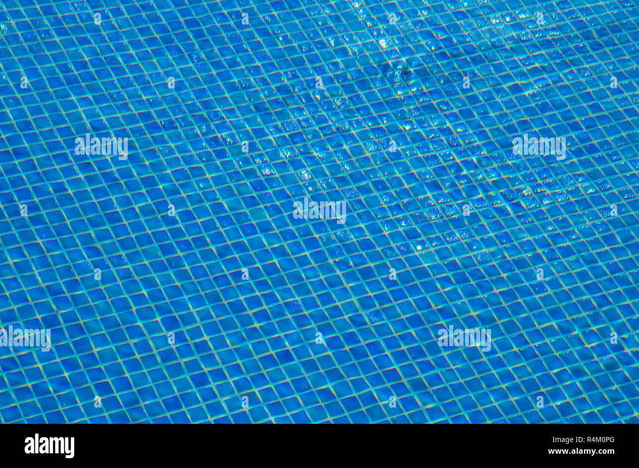 Detail of mosaic tile floor in a swimming pool seen through rippled ...
