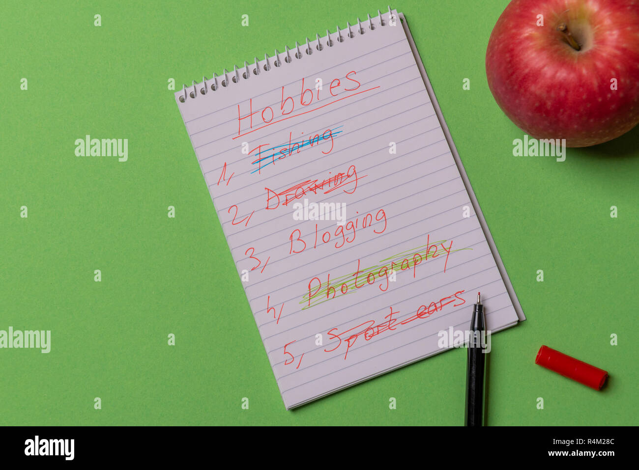 List of hobbies handwritten on a spiral notebook and a red apple on a ...