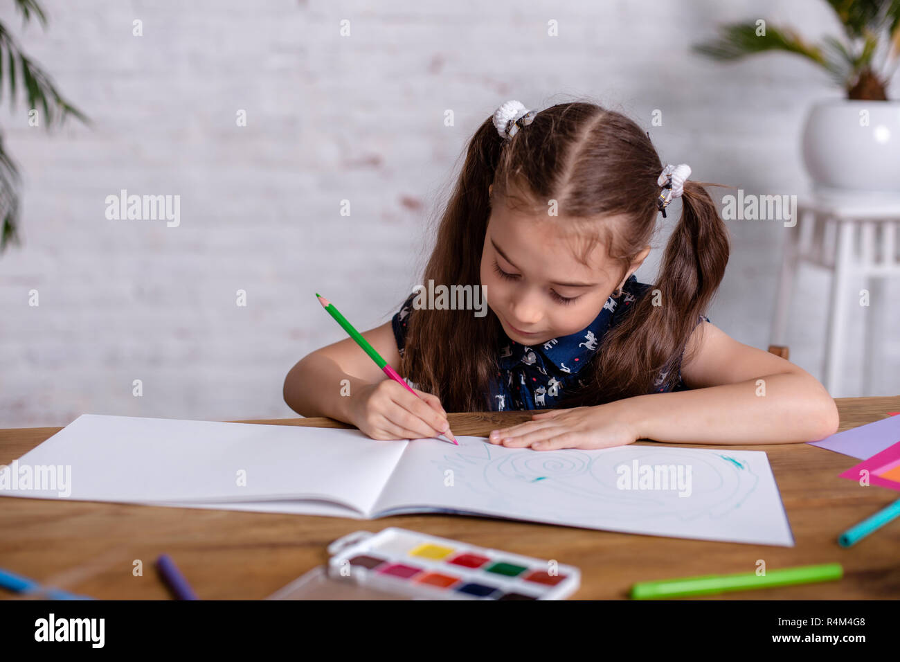 Inspired little girl at the table draw with crayons or do home work ...