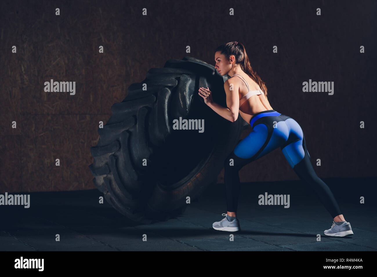 Fitness woman flipping wheel tire in gym. Fit female athlete working ...