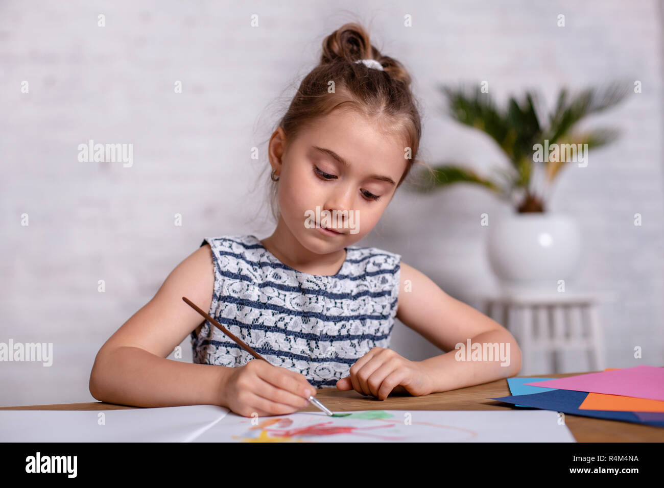 Inspired little girl at the table draw with paints. Studying in ...