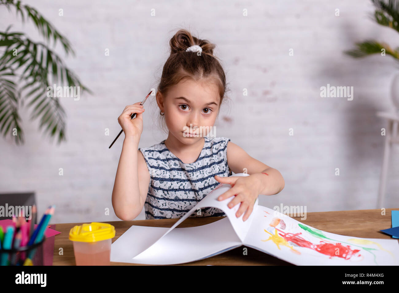 Inspired little girl at the table draw with paints. Studying in ...