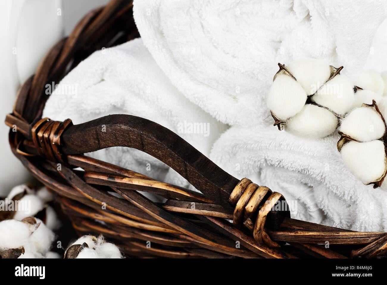Laundry basket filled white fluffy towels, cotton flowers and a bottle ...