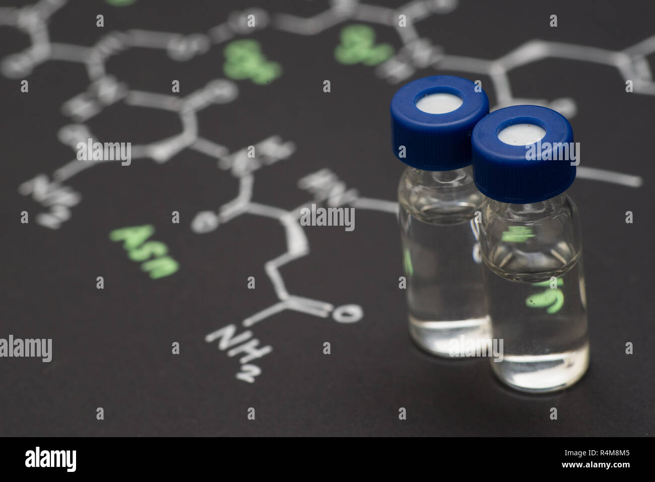Close-up blue cap sample vial on paper with chemical formula of ...
