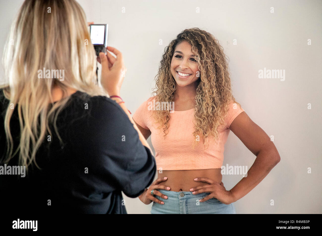 An informally dressed young woman smiles as she poses for her portrait ...