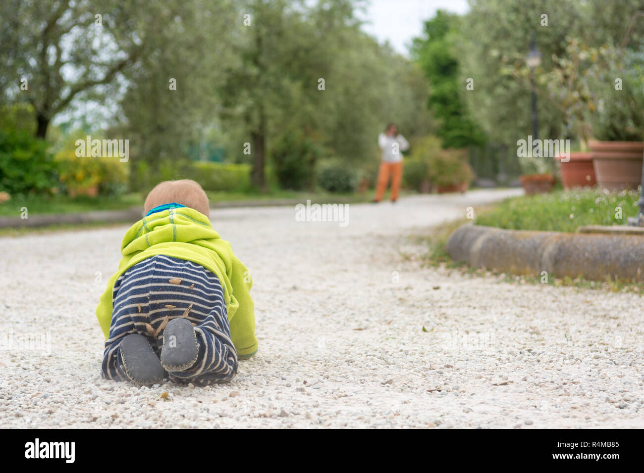 Rear view of a baby crawling towards her mother outdoor Stock Photo - Alamy