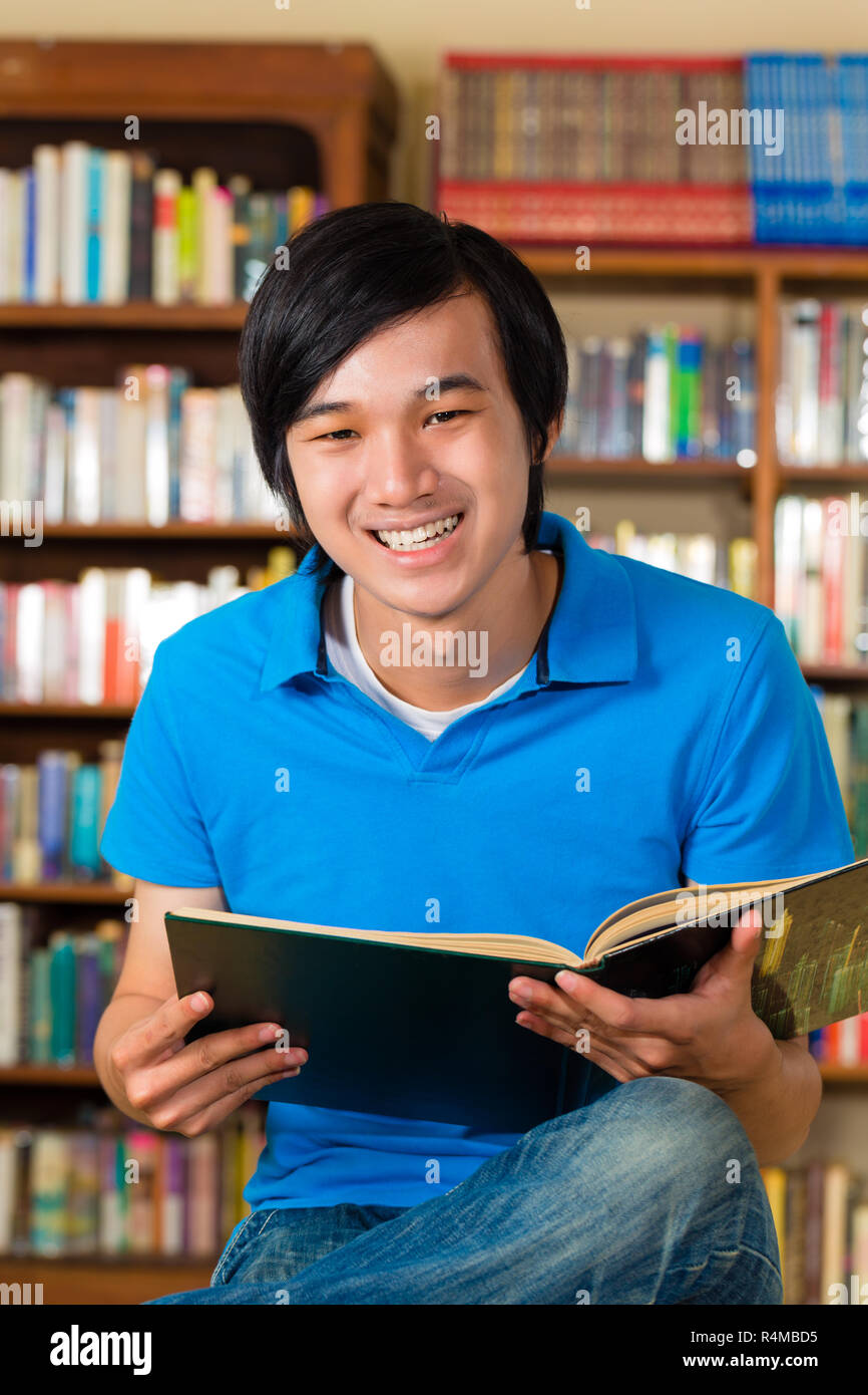 Student in library reading book Stock Photo - Alamy
