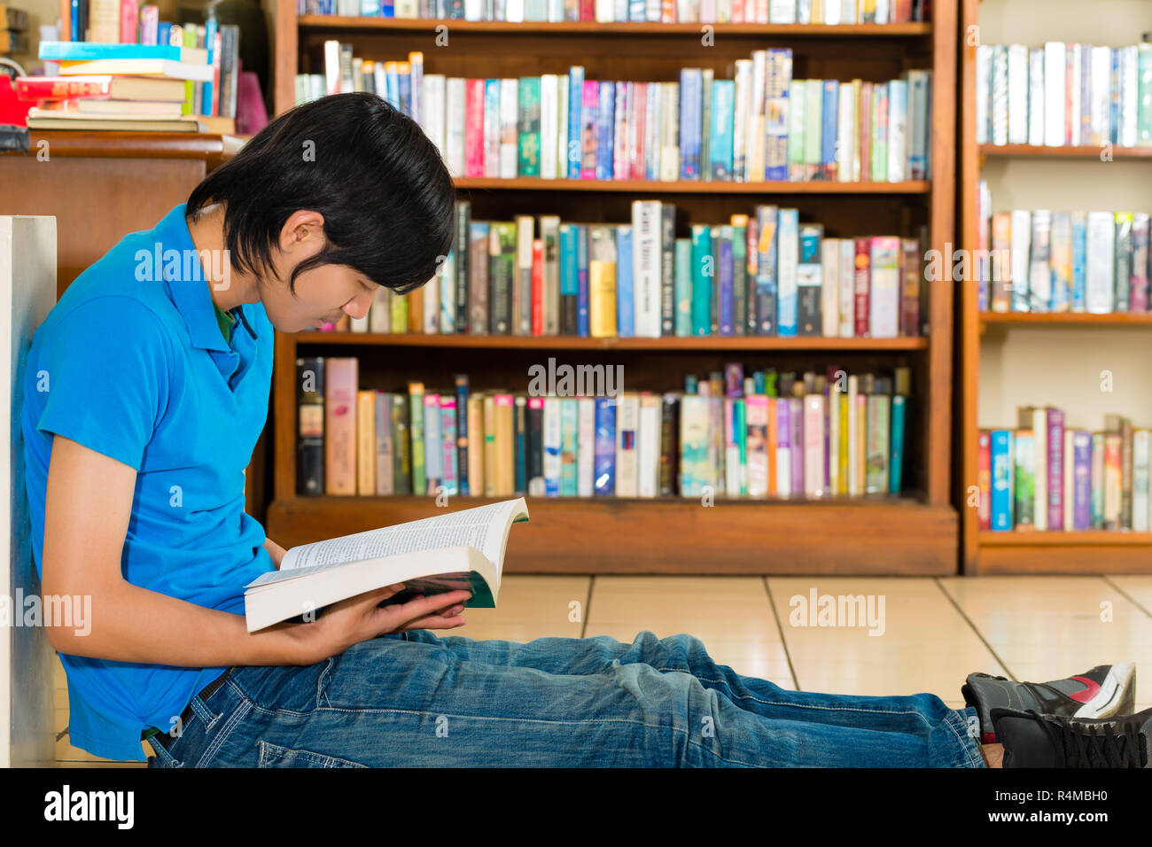 Student in library reading book Stock Photo - Alamy
