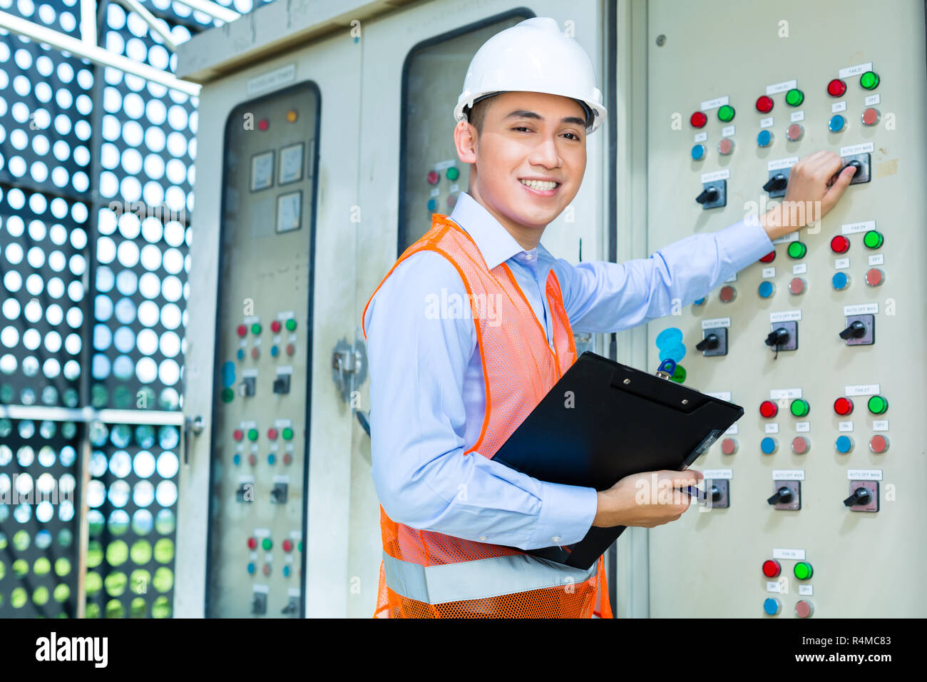 Asian technician at panel on construction site Stock Photo - Alamy
