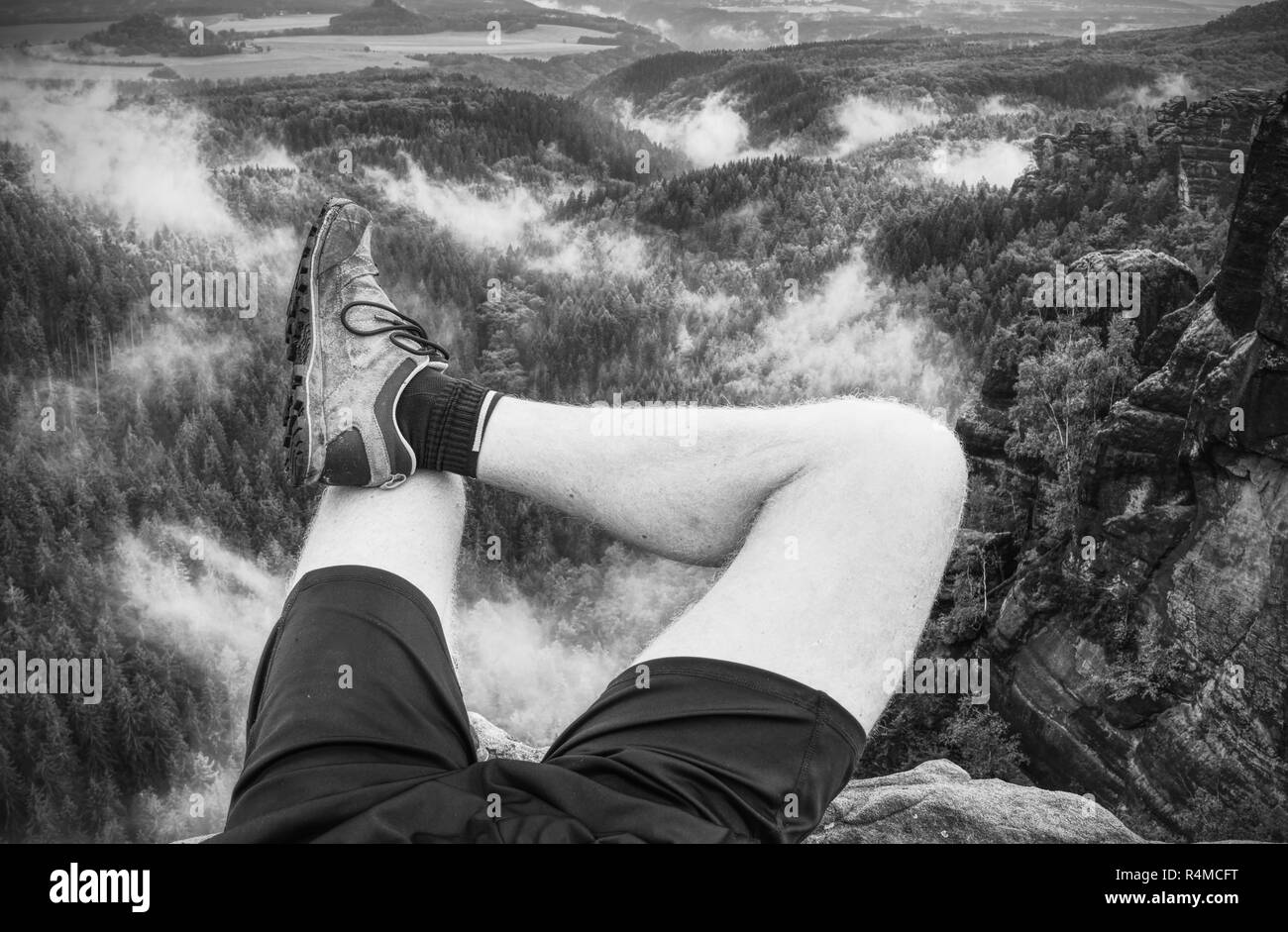 Hiker man take a rest on mountain peak. Male legs on sharp summit and ...