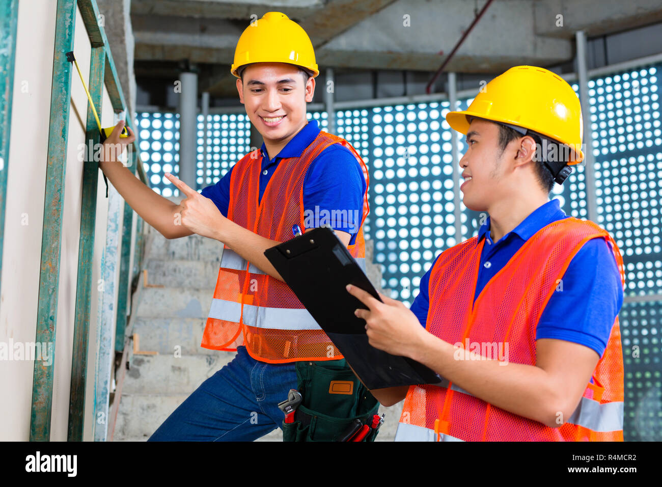 Asian worker controlling building on construction site Stock Photo - Alamy