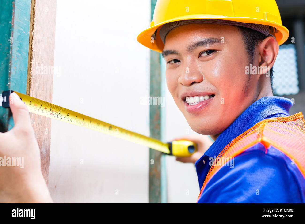 Builder or worker controlling wall on construction site Stock Photo - Alamy