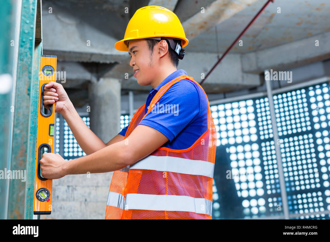 Builder or worker controlling wall on construction site Stock Photo - Alamy
