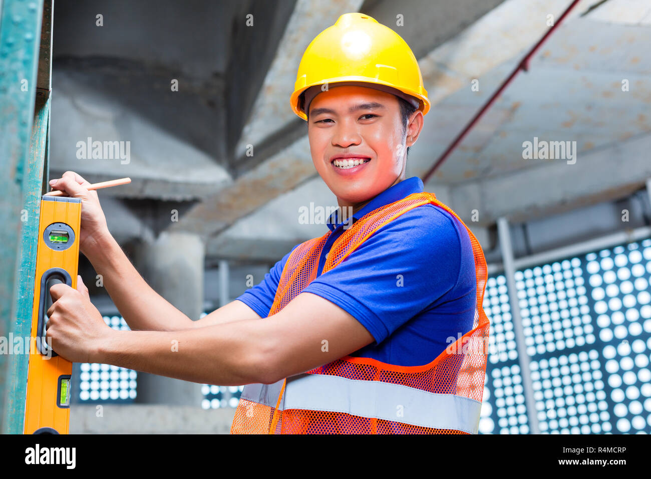 Builder or worker controlling wall on construction site Stock Photo - Alamy