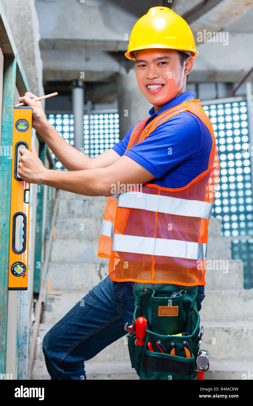 Builder or worker controlling wall on construction site Stock Photo - Alamy