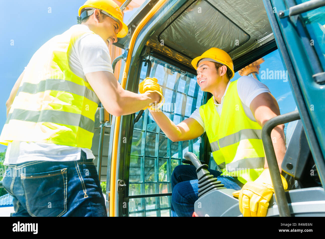 Two Asian workers with excavator on construction site Stock Photo - Alamy