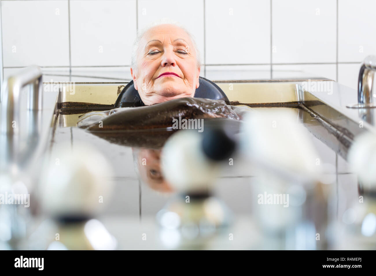 Senior woman enjoying mud bath alternative therapy Stock Photo - Alamy