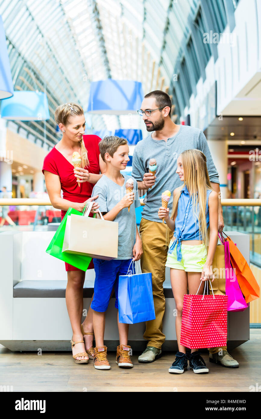 Family eating ice cream in shopping mall with bags Stock Photo - Alamy