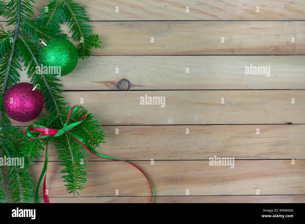 A spruce bough with red and green ornaments and a red and green ribbon ...