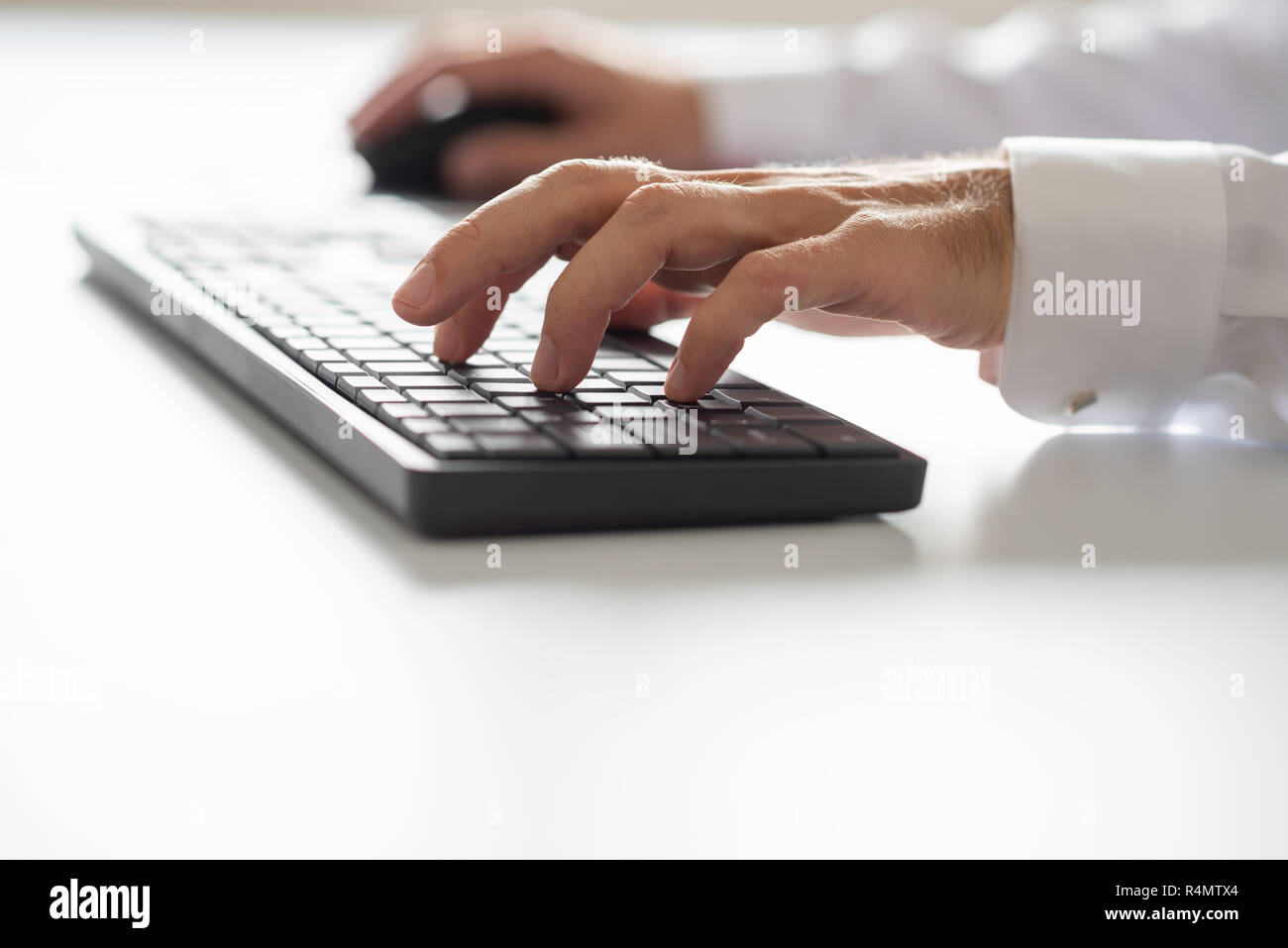 Closeup view of male hand using computer keyboard and mouse on a white ...
