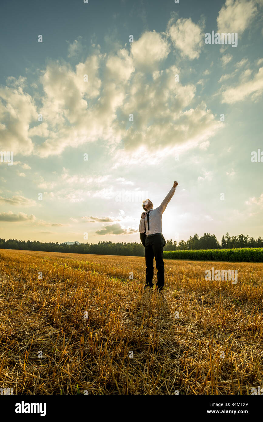 Businessman with one arm raised up high in success standing under ...