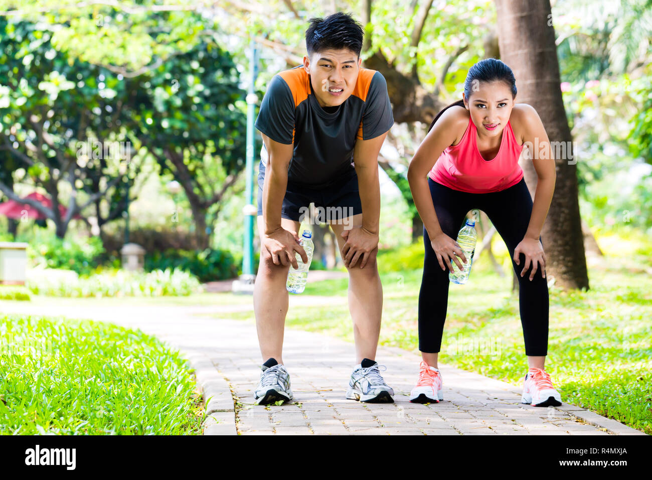 Asian couple take breathless break from running Stock Photo - Alamy