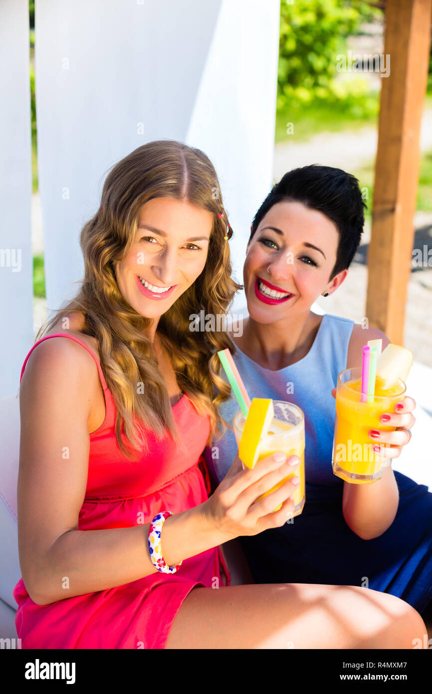 Two friends at lake beach with drinks relaxing Stock Photo - Alamy