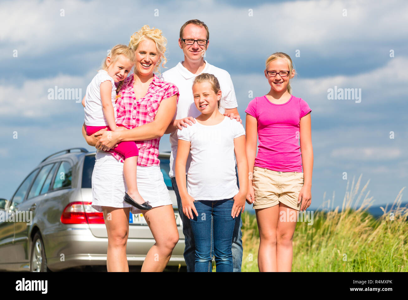 Family standing together in front of car Stock Photo - Alamy