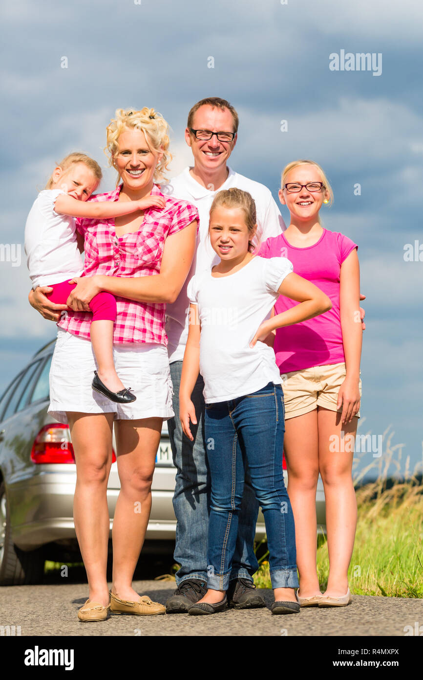 Family standing together in front of car Stock Photo - Alamy
