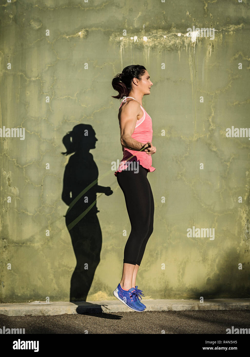 Woman skipping by concrete wall Stock Photo - Alamy