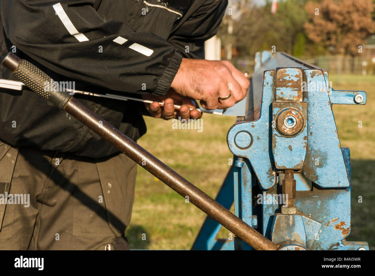 Man working on roof metal sheet in site construction. Man using special ...
