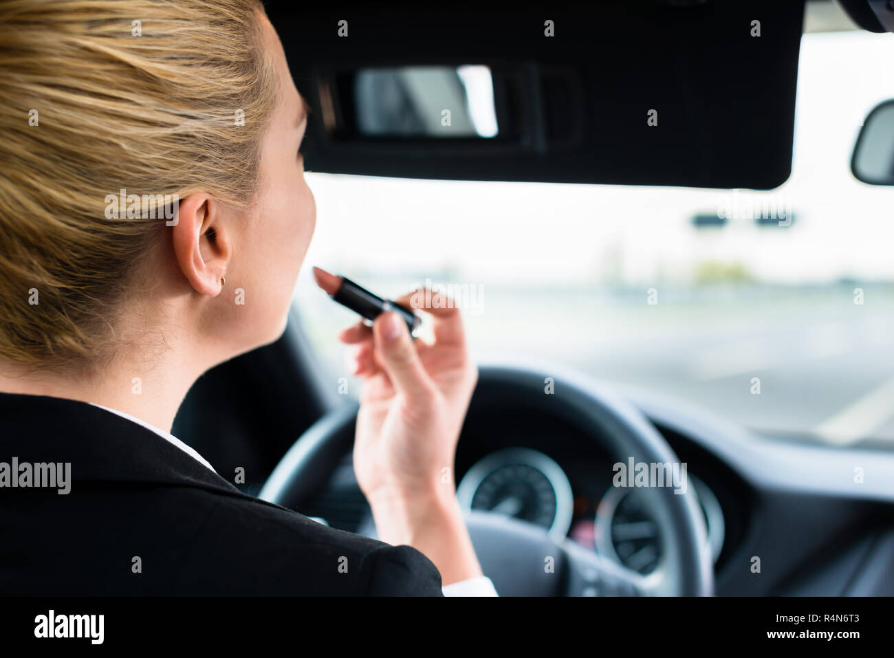 Woman applying lipstick using car hi-res stock photography and images ...