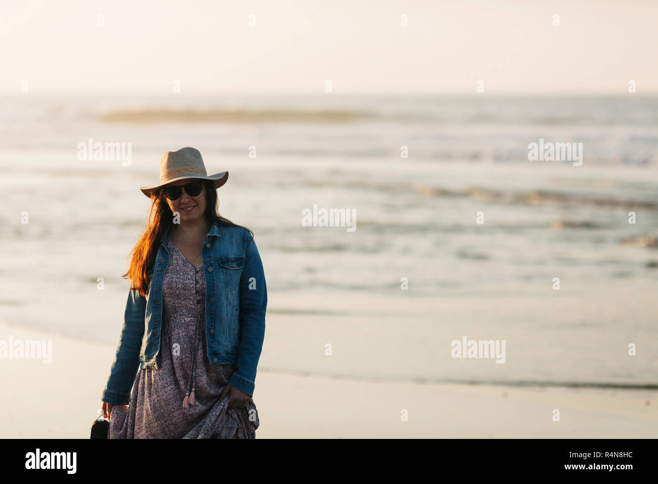 Woman in sunhat and denim jacket on beach Stock Photo - Alamy