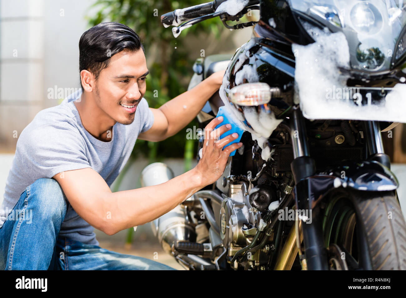 Asian man washing his motorcycle or scooter Stock Photo - Alamy
