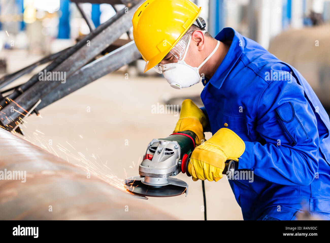 Metal worker in factory grinding metal of pipeline Stock Photo - Alamy