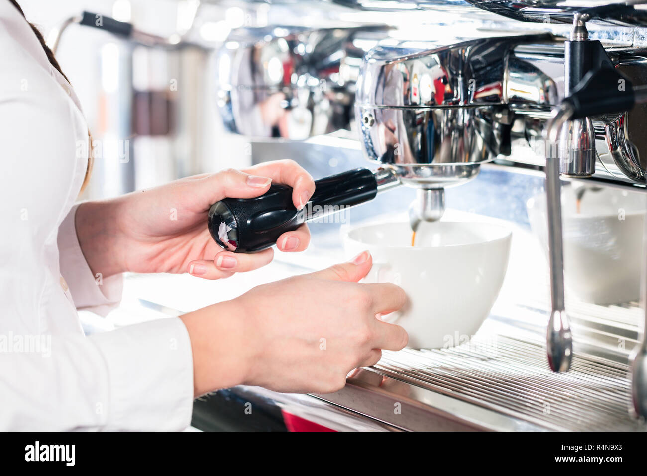 Close-up of female hand on the portafilter of an automatic coffee ...