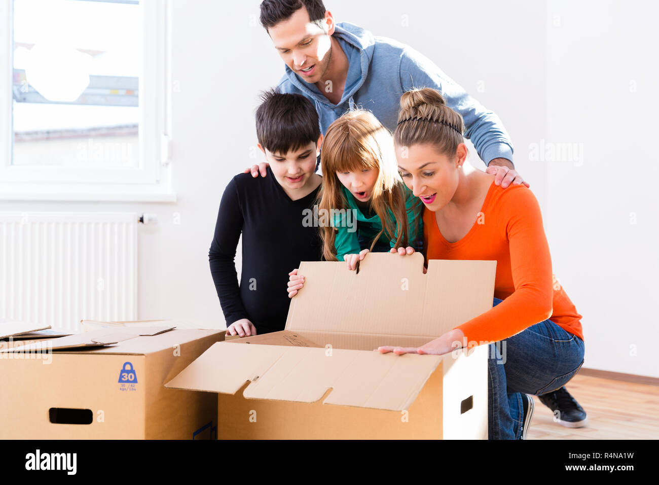 Family unpacking moving boxes in new home Stock Photo - Alamy