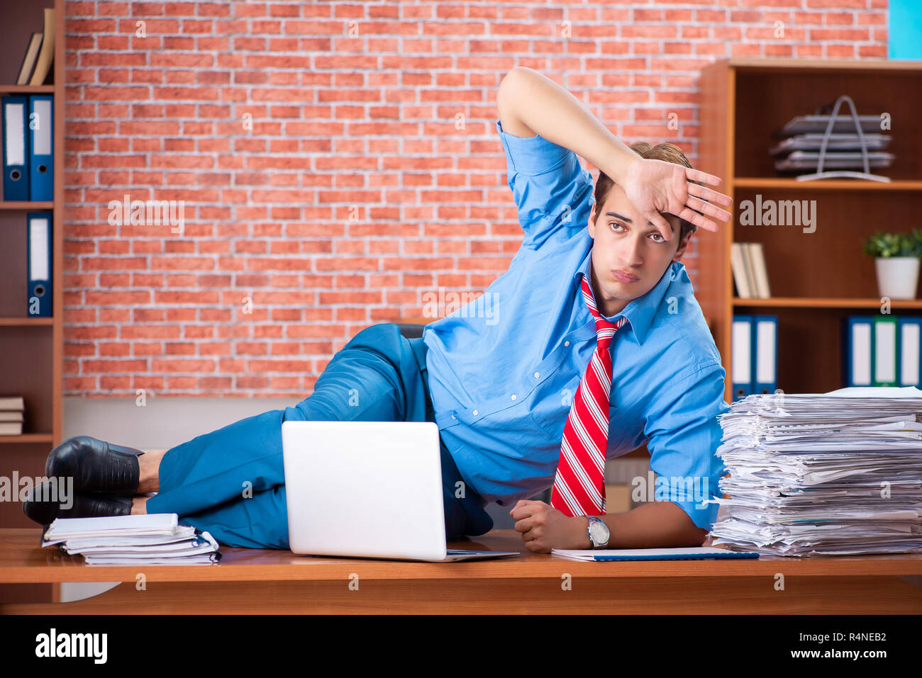 Young employee with excessive work sitting at the office Stock Photo ...