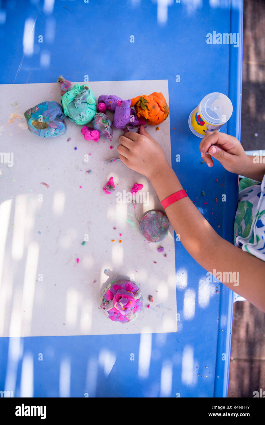 top view of kid hands Playing with Colorful Clay in outdoor Playground ...