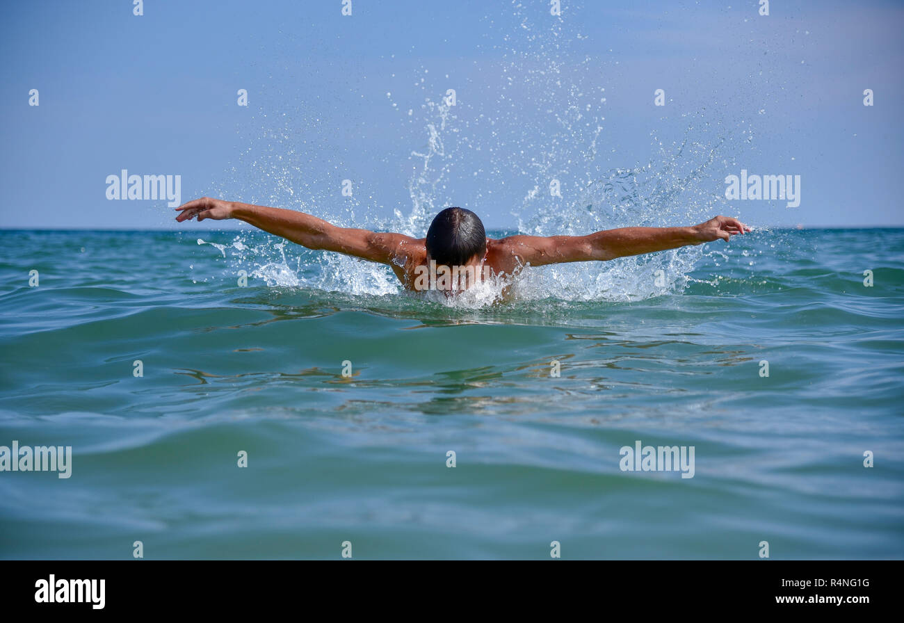 Swimmer in the open sea directly on camera half visible from the water ...