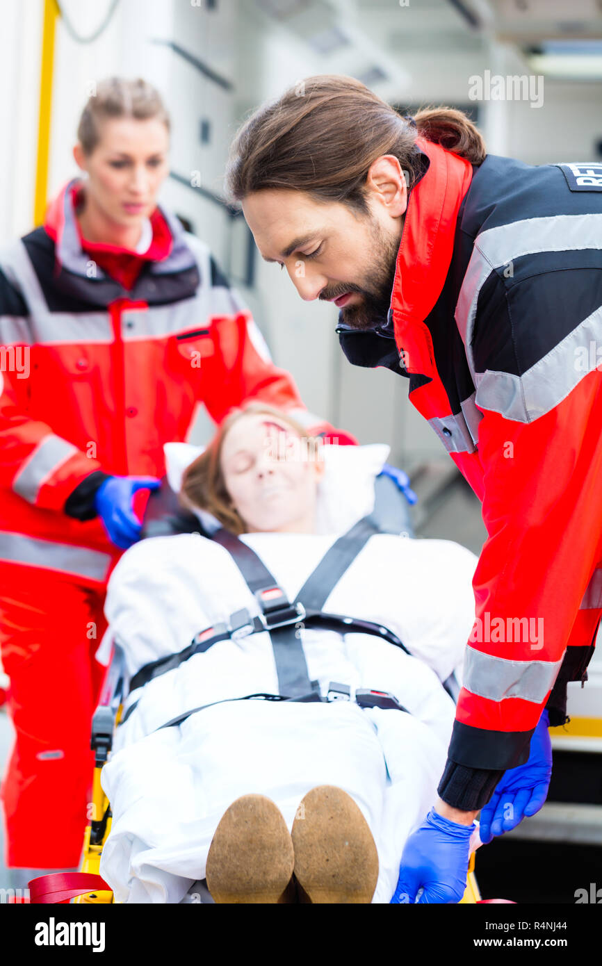 Ambulance helping injured woman on stretcher Stock Photo - Alamy