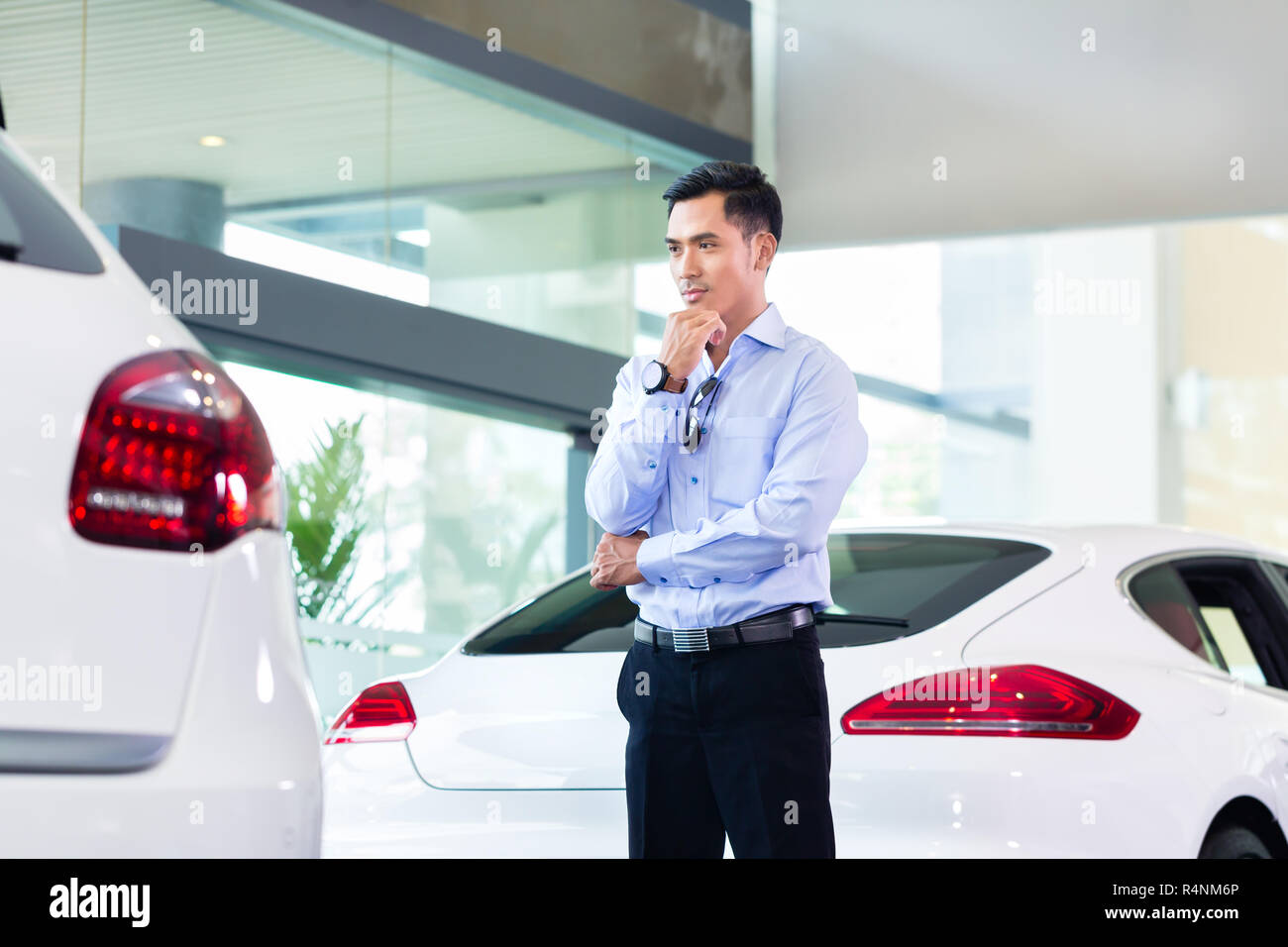 Asian man buying luxury car in dealership Stock Photo - Alamy
