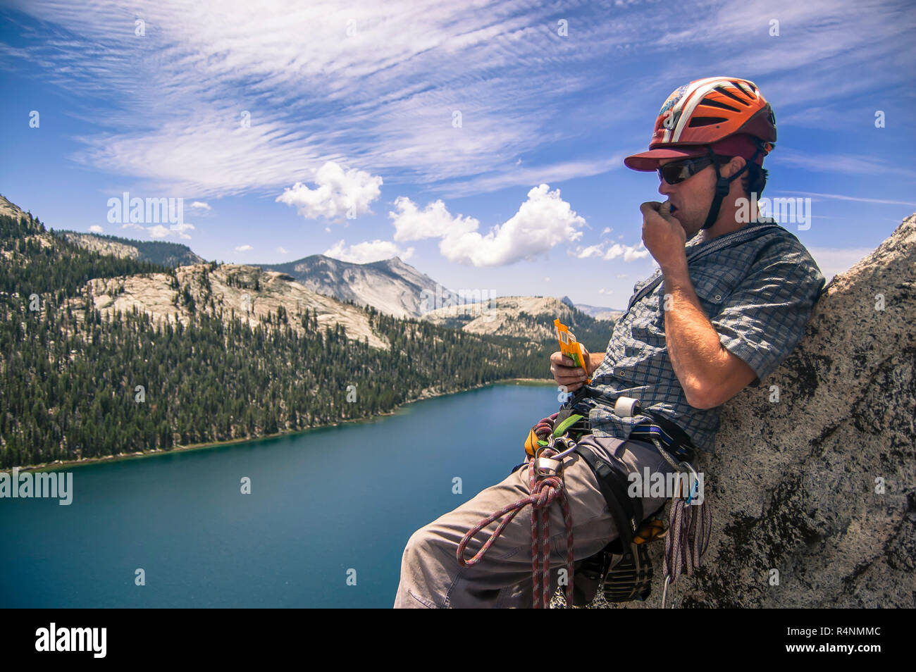 Man eating while rock climbing above lake in tuolumne meadows hi-res ...