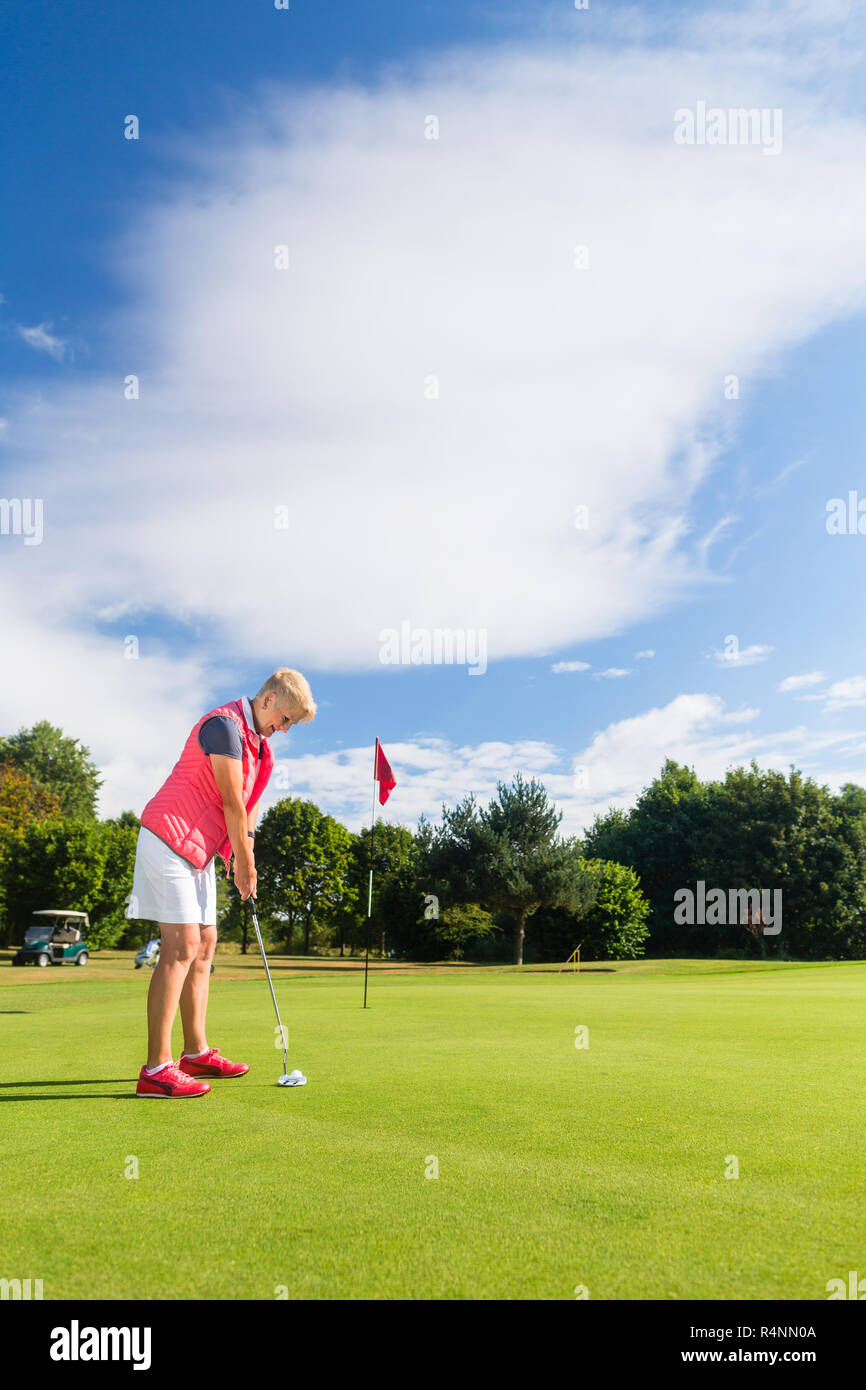 Senior golf playing woman putting on green Stock Photo - Alamy
